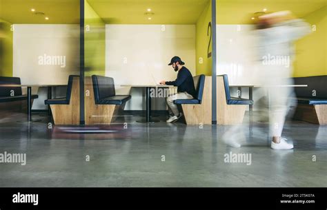 Software Developer Works On His Laptop In A Busy Coworking Office