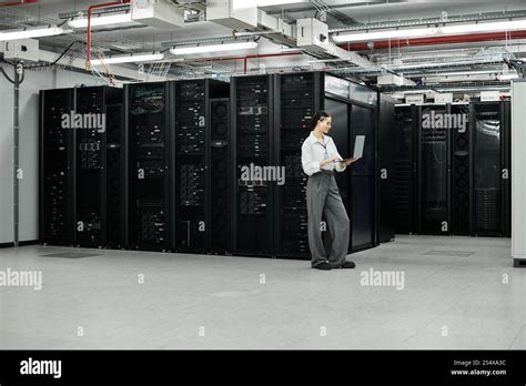 Professional Woman Works Diligently In A Sleek Server Room Overseeing