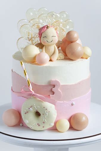 흰색 배경에 유니콘 그림 초콜릿 구체 카라멜 사탕으로 장식된 분홍색 파스텔 크림 치즈 프로스팅을 가진 소녀를 위한 생일 케이크 0명에 대한 스톡 사진 및 기타 이미지