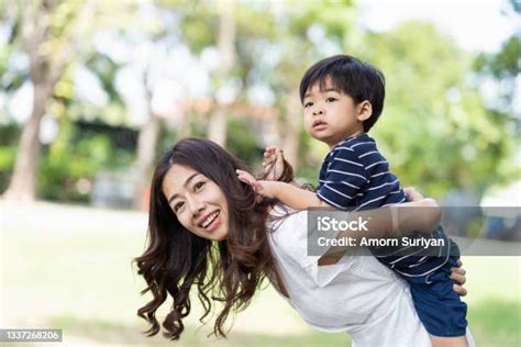 야외에서 함께 놀고 있는 행복한 아시아 가족 공원에서 휴가를 보내고 재미와 휴식을 취하는 쾌활한 어머니와 작은 아들 엄마는