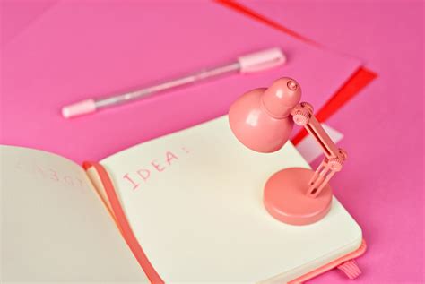 분홍색 배경에 노트북 노트북 근처의 장난감 테이블 램프 전자 필기장에 텍스트를 위한 공간과 여유 공간을 복사합니다 디자인모형 아이디어라는 단어는 연필로 작성되었습니다 창의성