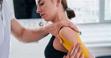 의료 사무실에서 특별한 운동 요법 재활 요법으로 전문 마사지 치료를 받는 아름답고 우아한 빨간 머리 여성 환자의 자른 머리 측면