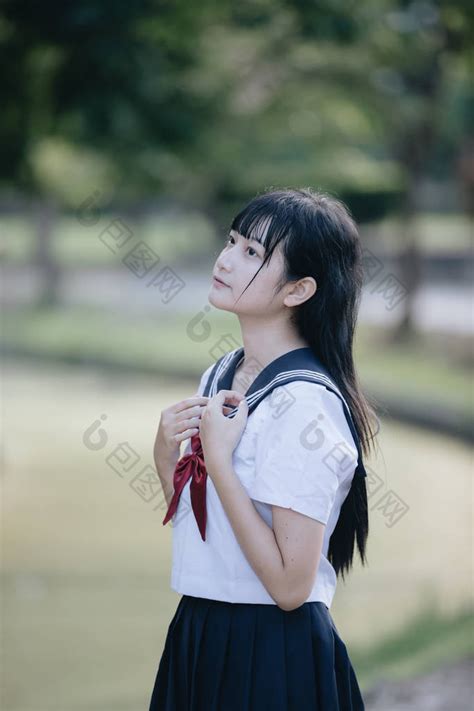 亚洲日本学校女孩服装与小花漫步在公园户外图片 包图网企业站