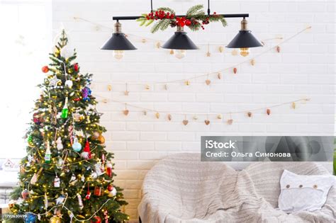 밧줄에 유리 장난감의 화환과 로프트 스타일의 벽돌 벽이 있는 집의 흰색 인테리어에 크리스마스 트리 스튜디오 룸의 빛나는 요정 조명 장식 크리스마스와 새해에 아늑한 숙소 0
