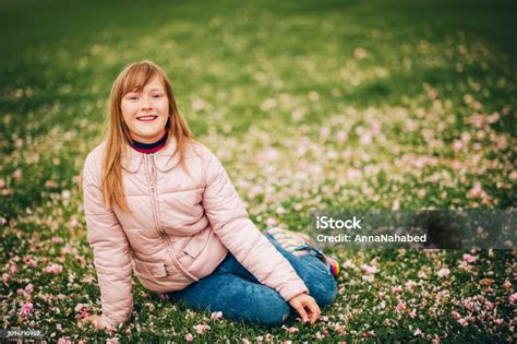 밝은 녹색 잔디에 쉬고 부드러운 꽃 꽃잎 봄 공원에 놀고 패딩된 재킷 아이 들을 위한 계절 패션을 입고 재미 있는 어린 소녀 4월에 대한 스톡 사진 및 기타 이미지 Istock