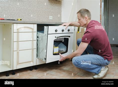Installation Of Kitchen Furniture The Man Is Pushing The Built In Electric Oven In The Cabinets