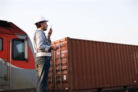 안전모와 안전조끼를 입고 컨테이너 화물을 점검하고 화물 열차 근처 역에서 워키토키로 작업하는 중동 남성 철도 노동자 객차에 대한 스톡 사진 및 기타 이미지 Istock