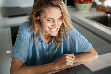 부엌에 앉아있는 동안 노트북 화면에 콘텐츠를보고 미소 중간 성인 여성 30 34세에 대한 스톡 사진 및 기타 이미지 30 34세 30 39세 가정 주방 Istock