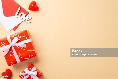 발렌타인 데이 개념입니다 흰색 리본 활이 있는 빨간색 선물 상자의 상위 뷰 사진 종이 시트 하트 모양의 양초와 비문 사랑이 있는 격리된 파스텔 베이지색 배경에 복사 공간 0