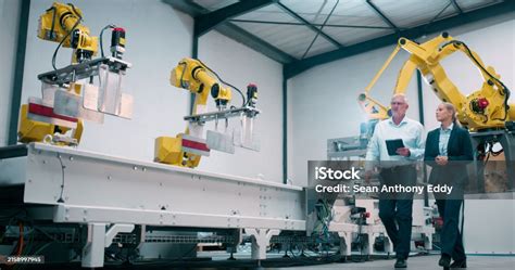 인더스트리 40 및 제조 검사를 위한 공장의 로봇 공학 팀워크 및 자동화 기술자 조립 라인에서 기술을 위한 디지털 태블릿을 들고 걷고 있는 엔지니어링 여성 또는 고위 관리자