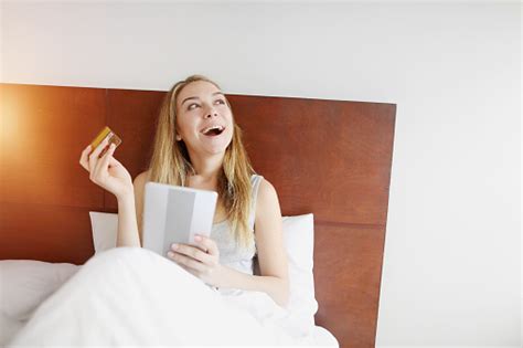 여자는 직불 신용 카드를 보유하고 태블릿은 햇빛과 집에서 흰색 침대에 누워 측면에 보인다 고름에 대한 스톡 사진 및 기타 이미지 고름 구매 금발 머리 Istock