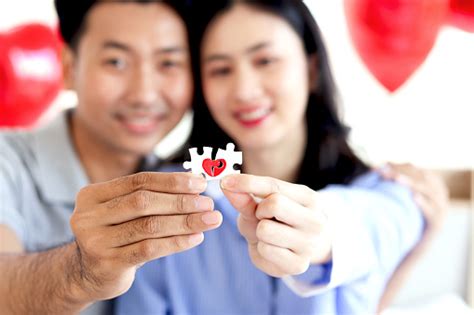 빨간 하트를 형성하는 퍼즐 두 조각을 들고 카메라에 보여주는 행복한 아시아 커플 연인 손에 퍼즐 조각에 하트 발렌타인 데이에 기념일을 축하하는 낭만적인 연인 사랑 개념입니다