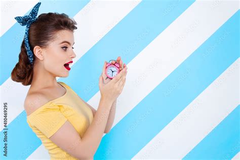 Sexy Surprised Woman With Alarm Clock In Hands And Open Mouth Colorful Background In Pop Art