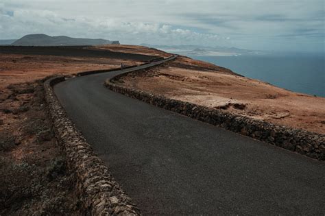 좁은 아스팔트 도로는 란사로테의 건조한 화산 지형을 통과하여 구불구불합니다 건조한에 대한 스톡 사진 및 기타 이미지 건조한