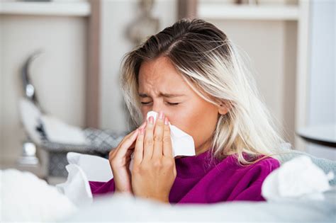 아픈 여자독감여자는 감기에 걸렸습니다 조직으로 재채기 두통 바이러스 의약품 젊은 여자 감염 에 감기 불고 그녀의 코 에 손수건 소파에 앉아 두통을 가진 아픈 여자 감기와