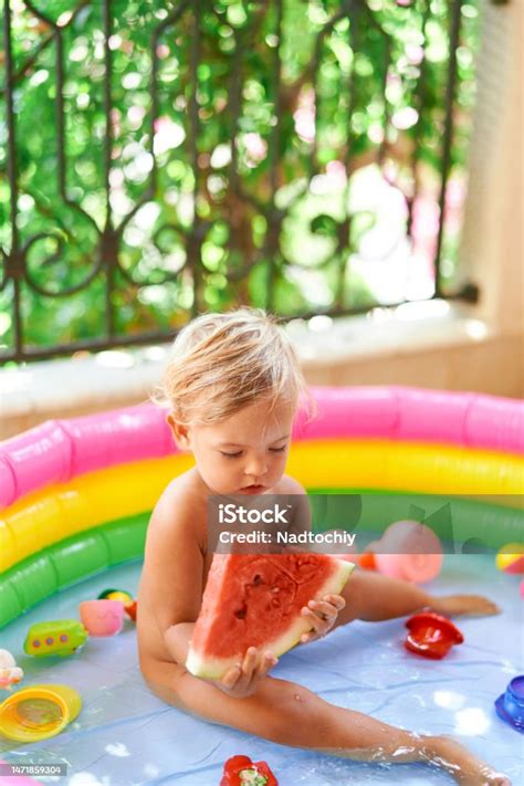 어린 소녀는 발코니의 풍선 수영장에 수박 조각을 손에 들고 앉아 있다 고여 있는 물에 대한 스톡 사진 및 기타 이미지 고여 있는 물 공기 주입 과일 Istock