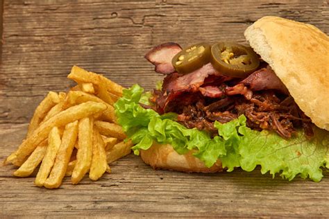 바베 큐 뽑아 샌드위치 Beff 그린 샐러드 파 삭 파삭한 베이컨 고추 Jalapeno 바베 큐 소스와 나무 배경 패스트 푸드