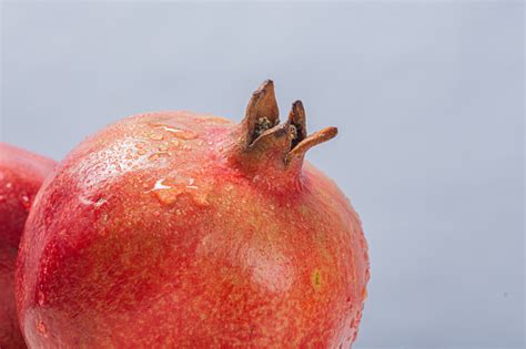 젖은 흰색 표면과 밝은 배경에 물방울이 있는 두 개의 통째로 빨간 석류는 항산화 물질이 풍부한 과일의 생생한 피부 질감과 열대의 신선함을 보여줍니다 겉껍질에 대한 스톡 사진