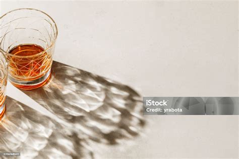 음료와 크리스탈 안경 베이지 색 질감의 배경 최소한의 트렌드 미적 측면보기 반짝이는 유리 태양 눈부심 강한 알코올 음료 개념 여름철에 햇빛에서 아름다운 그림자 갈색에 대한