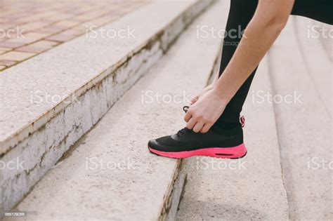자른된 사진 야외 계단에 훈련에 여자 검은색과 분홍색 운동 화에 끈을 매는 여성 손의 닫습니다 휘트니스 건강 한 라이프 스타일 개념입니다 광고에 대 한 공간을 복사 합니다