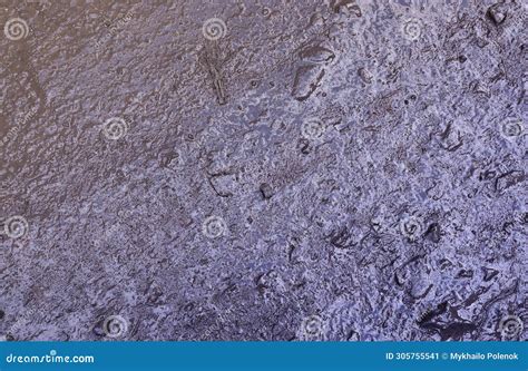 Close Up Of Muddy Puddle With Small Stones On Wet Surface Background