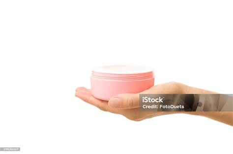 젊은 성인 여성의 손을 잡고 흰색 배경에 고립 된 열린 분홍색 보습 크림 항아리를 보여줍니다 깨끗하고 부드러운 바디 피부를 케어합니다 근접 촬영 앞 모습 건강관리와 의술에