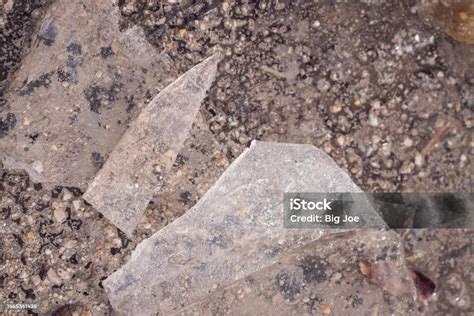 겨울 눈과 얼음이 녹기 시작하면서 젖은 흙과 모래 위에 누워 있는 뾰족한 깨진 얼음 조각의 겨울 배경 이미지를 닫습니다 갈색에 대한 스톡 사진 및 기타 이미지 Istock