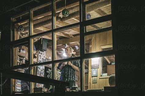 Man Drinking Tea While Looking Out Window Of Country Cottage In Rural Lakeside Canada By