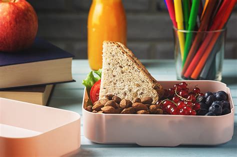 야채 아몬드 너트 베리를 용기에 넣고 샌드위치 책에 사과 유리 병에 오렌지 주스와 배경에 컵에 여러 가지 빛깔의 연필 직장에서의 건강한 아침 식사 0명에 대한 스톡 사진 및