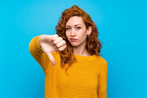 빨간 머리 여자 와 노란색 스웨터 보여주는 엄지 손가락 아래로 와 부정적인 표정 노랑에 대한 스톡 사진 및 기타 이미지 노랑 머리 모양 몸짓 Istock