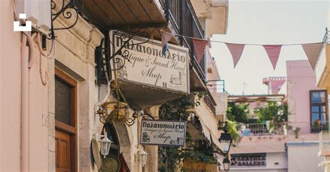 낮에는 갈색 콘크리트 건물 옆에 갈색 나무 테이블과 의자가 있습니다 사진 Unsplash의 무료 그리스 이미지