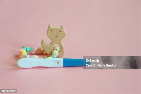 구슬과 임신 테스트와 나무 아기 이빨 나무 장난감 고양이 고립 된 분홍색 배경과 미니멀 플랫 누워 어린이와 부모를 즐겁게장난감