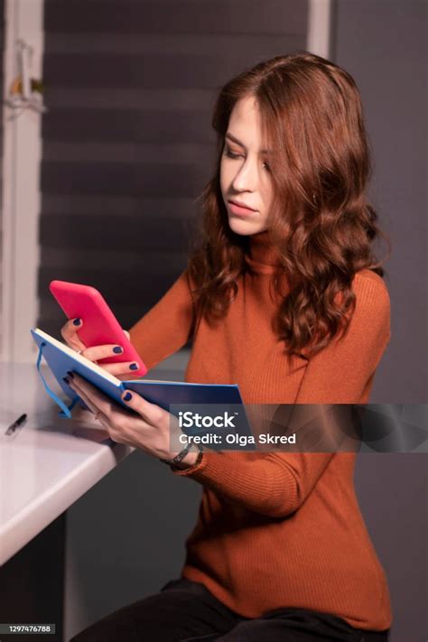 회색 방에 테이블에 앉아 분홍색 케이스에 파란색 노트북과 전화와 갈색 골프에서 매력적인 갈색 갈색 여자 일 교육 연구 갈색에 대한 스톡 사진 및 기타 이미지 Istock