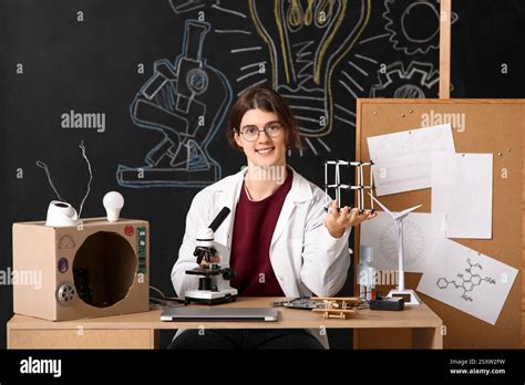Male Inventor With Molecular Model And Microscope At Table In Workshop