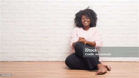 섹시 한 표정 명랑 하 고 행복 한 얼굴을 카메라 보고 윙크 하는 집에서 바닥에 앉아 젊은 아프리카계 미국인 여자 바닥재에 대한 스톡 사진 및 기타 이미지 Istock
