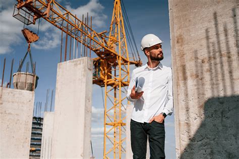 서서 계획을 손에 들고 있습니다 제복을 입은 남자가 건설 현장에서 일하고 있다 25 29세에 대한 스톡 사진 및 기타 이미지 25 29세 강철 건설 산업 Istock