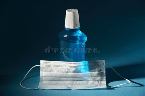 Blue Sanitizer In A Large Bottle And A Medical Face Mask Dark