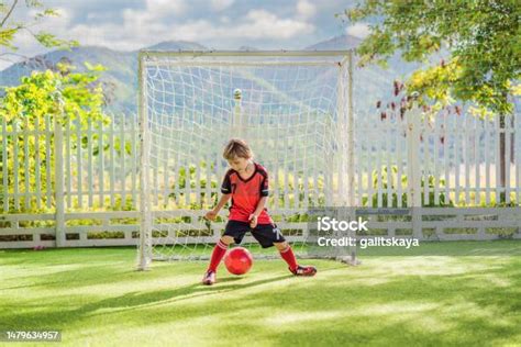 빨간 축구 유니폼을 입은 귀여운 소년이 야외에서 축구 축구를 하고 있다 아이들이나 아빠와 함께 스포츠를 하는 활동적인 아이 여름에 즐거운 미소를 짓는 행복한 소년 6 7