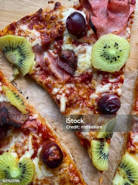 갓 구운 삼각형 조각 수제 피자 적포도 햄 키위 조각 강판 모짜렐라 치즈 토핑 풍부한 토마토 소스 기름칠 방지 양피지 배경 높은 전망의 클로즈업 이미지 0명에 대한 스톡