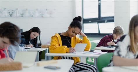 고등학교 피곤한 학생들은 수업에서 메모를 쓰고 책상에 앉아 학교 개념으로 돌아갑니다 사진 Unsplash의 교실 이미지