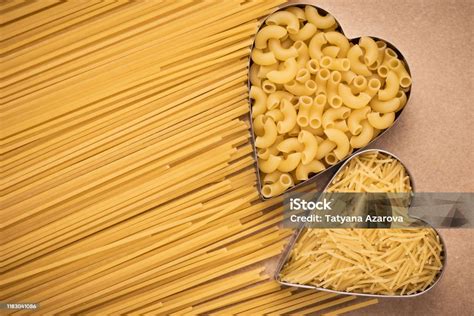 갈색 종이 배경에 파스타의 두 마음 양피지에 원시 스파게티의 힙 맨 위 보기 조리되지 않은 마카로니의 질감 전통 이탈리아 요리 사랑의 상징 마음의 모양 갈색에 대한 스톡