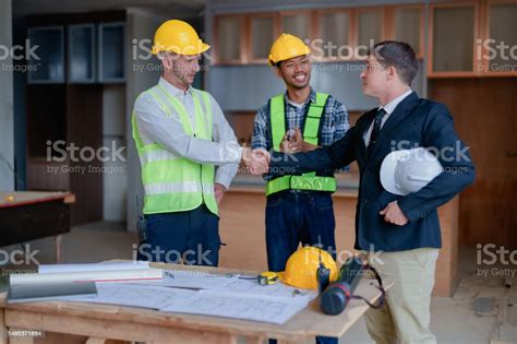 다민족 엔지니어가 서류 작업 및 평면도 도면 계약 및 계약 개념에 대한 비용 추정을 위해 거래 및 측정에 대해 브레인스토밍합니다