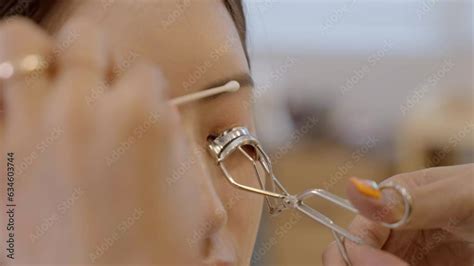 면봉으로 눈꺼풀을 누르고 눈썹뷰러로 속눈썹을 올리고 있는 손 Stock Video Adobe Stock