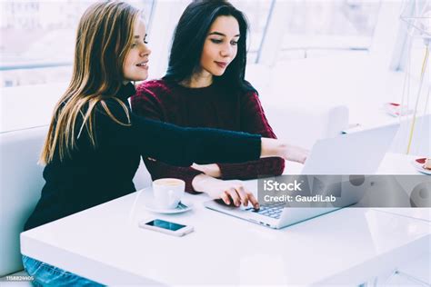 귀여운 금발 동료와 함께 시간을 보내는 동안 노트북 컴퓨터를 가리키는 긍정적 인 좋은 찾고 금발 디자이너 젊은 힙스터 여자 작업