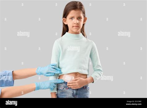 Doctor Applying Medical Patch On Girls Belly After Appendectomy Surgery On Light Background