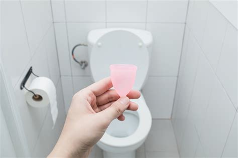 젊은 여성이 화장실 앞에서 생리컵을 들고 있다 생리 중 여성 위생 제품 개념을 대체합니다 제로 폐기물과 재사용 가능 환경 친화적 인 방법 건강관리와 의술에 대한 스톡 사진