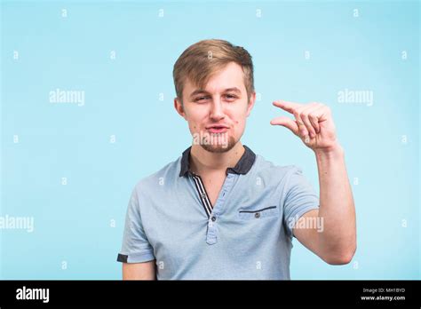 Positive Handsome Man Shows Something Very Tiny Or Small Over Blue