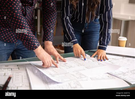 Close Up With The Hands Of Two Architects Analyzing Some Sketches Blueprints On The Table Stock
