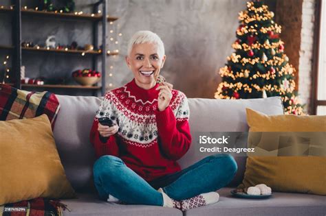 예쁜 늙은 아가씨의 전신 초상화 Tv 원격 제어 먹다 쿠키 새해 크리스마스 시간 평면 실내 55 59세에 대한 스톡 사진 및 기타 이미지 55 59세 강림절 계절