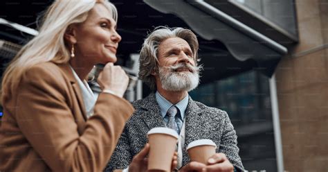 쾌활한 수염을 기른 남자가 아내 근처에 커피를 마시며 서 있는 동안 시선을 돌린다 사진 Unsplash의 기쁨 이미지